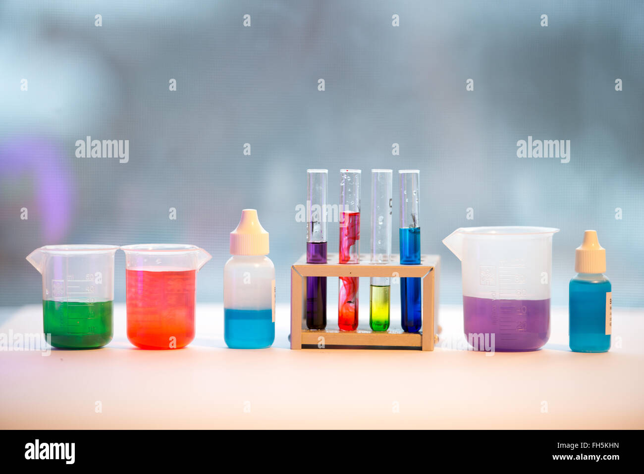 Row of colorful vials, beakers and droppers against an out-of-focus ...