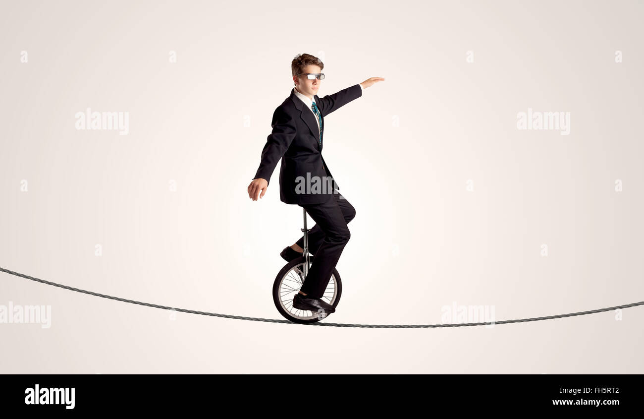 Extreme business man riding unicycle on a rope Stock Photo - Alamy