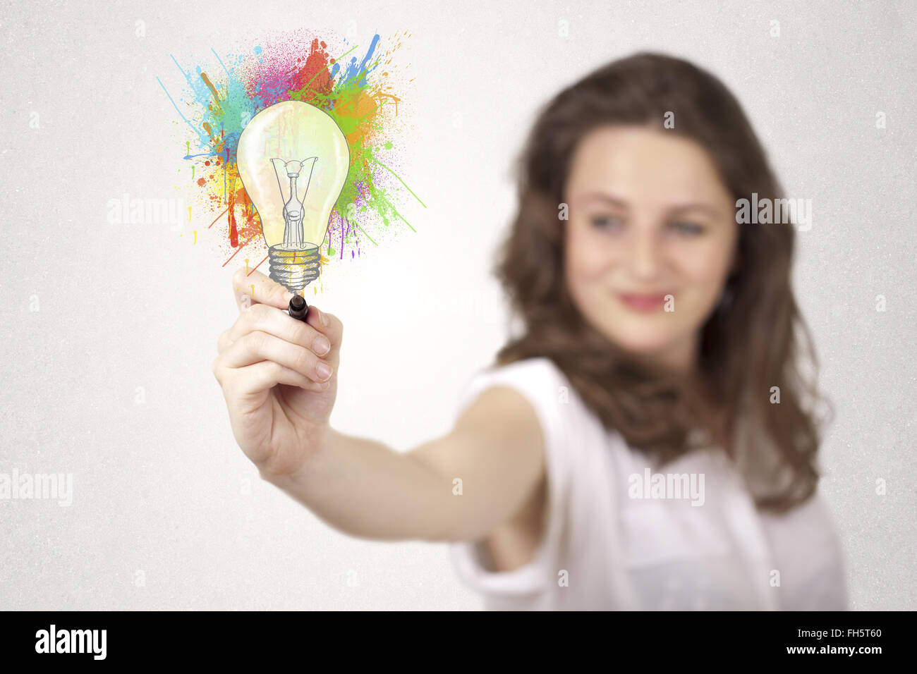 Young lady drawing a colorful light bulb with colorful splashes Stock ...