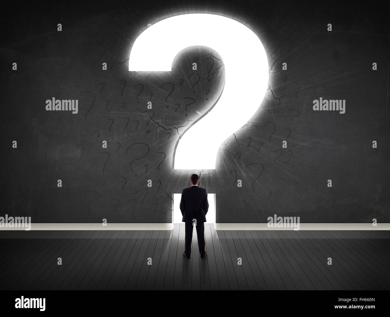 Business man looking at wall with a bright question mark Stock Photo ...