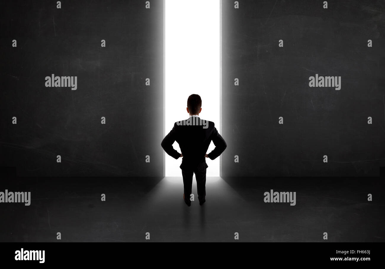 Business person looking at wall with light tunnel opening Stock Photo ...