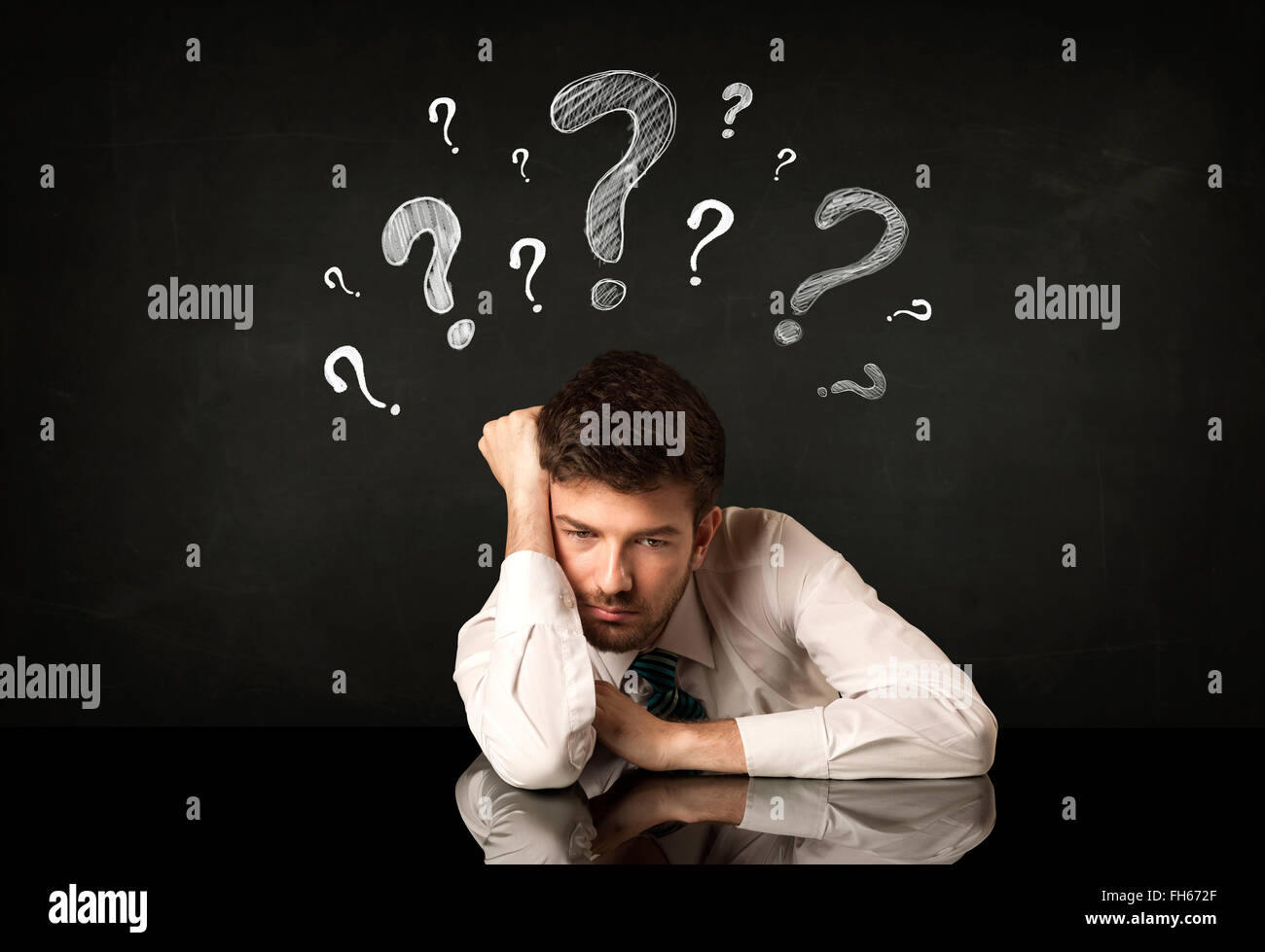 Sitting businessman under question marks Stock Photo - Alamy