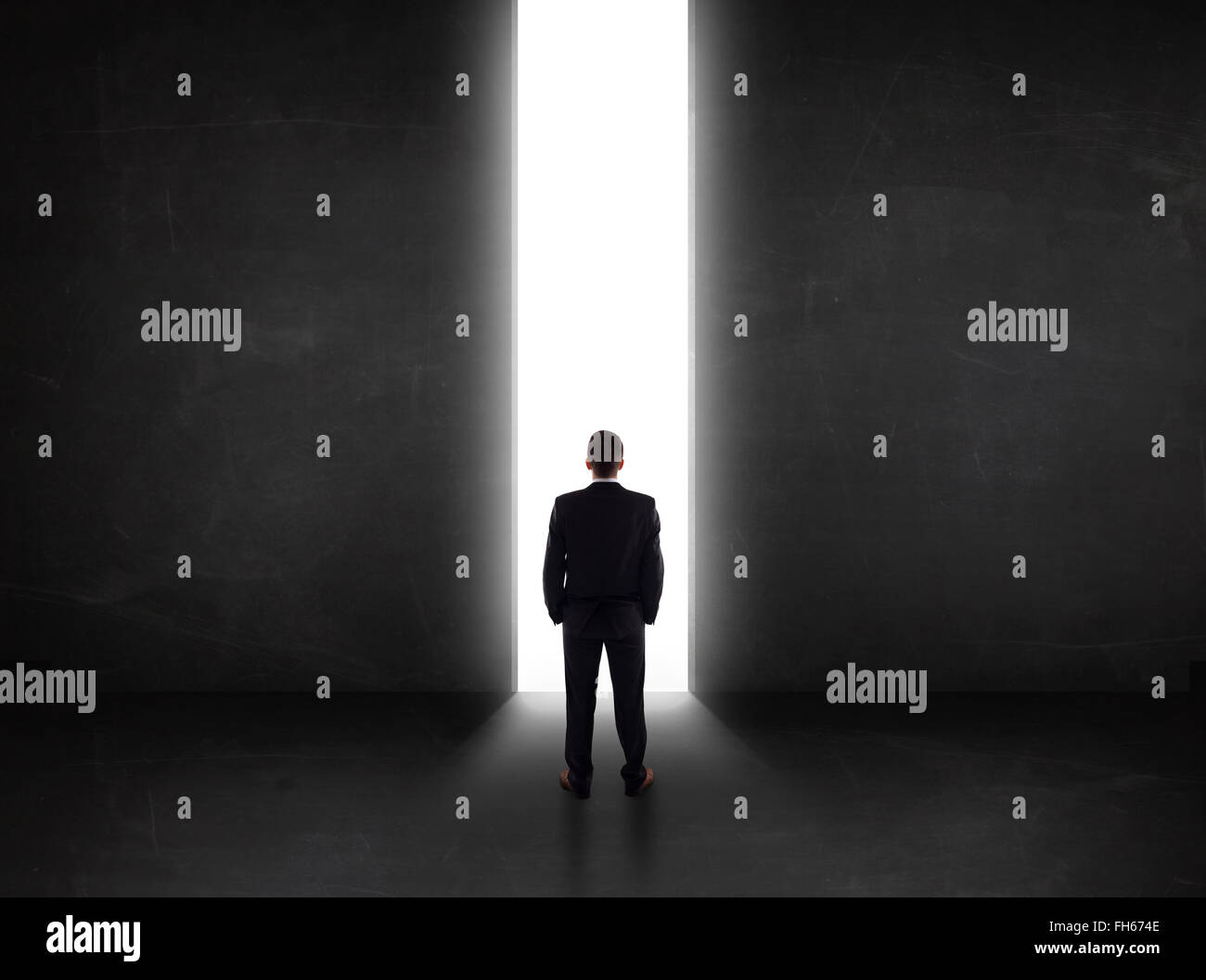 Business person looking at wall with light tunnel opening Stock Photo ...