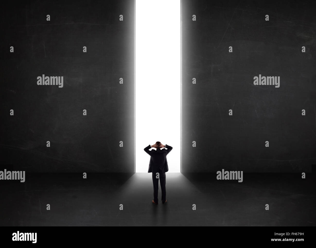 Business person looking at wall with light tunnel opening Stock Photo ...