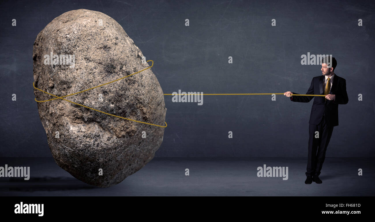 Businessman pulling huge rock with a rope Stock Photo - Alamy