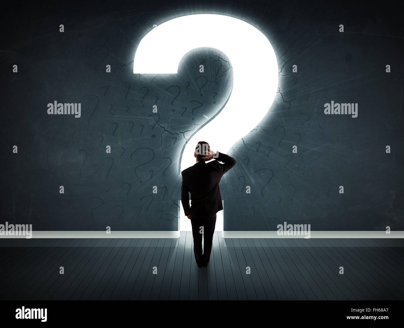 Business man looking at wall with a bright question mark Stock Photo ...