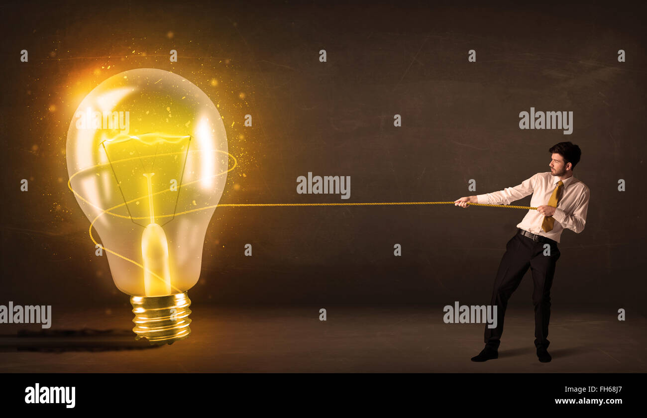 Business man pulling a big bright glowing light bulb Stock Photo - Alamy