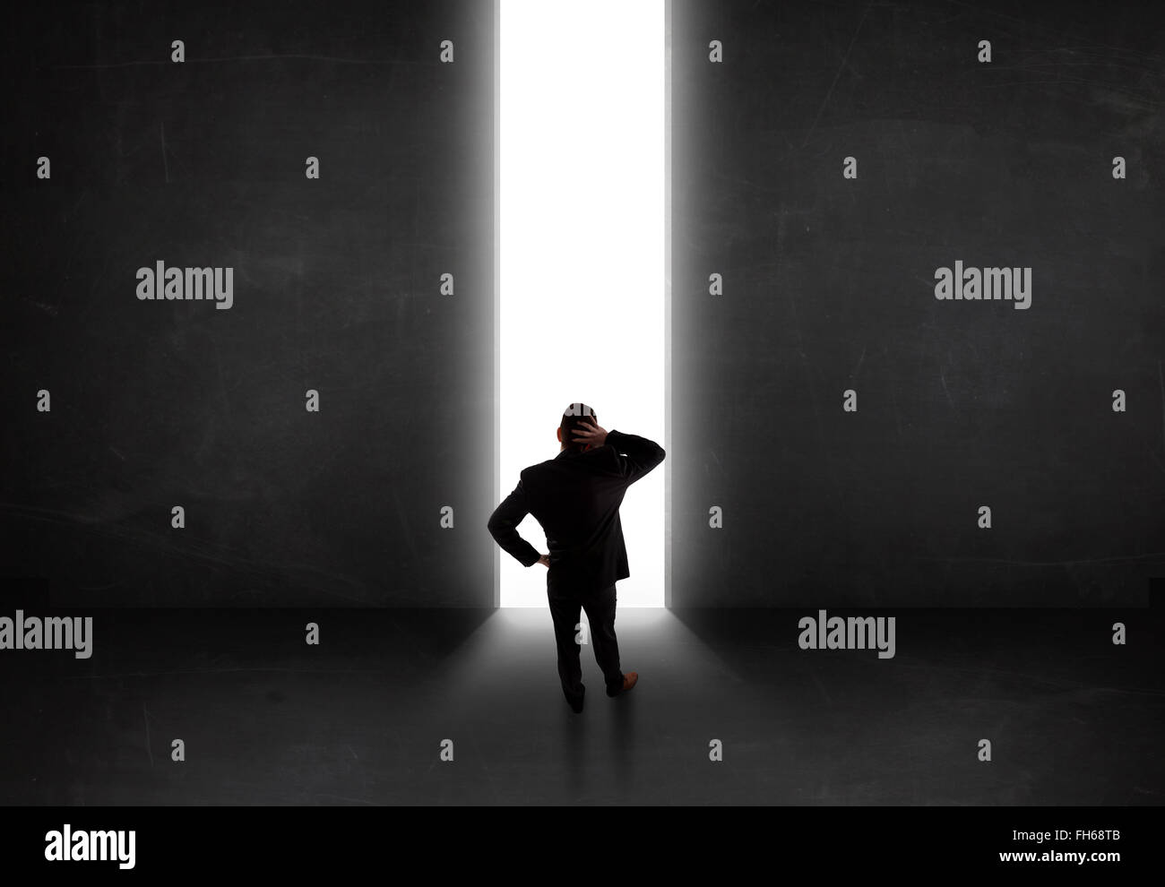 Business person looking at wall with light tunnel opening Stock Photo ...