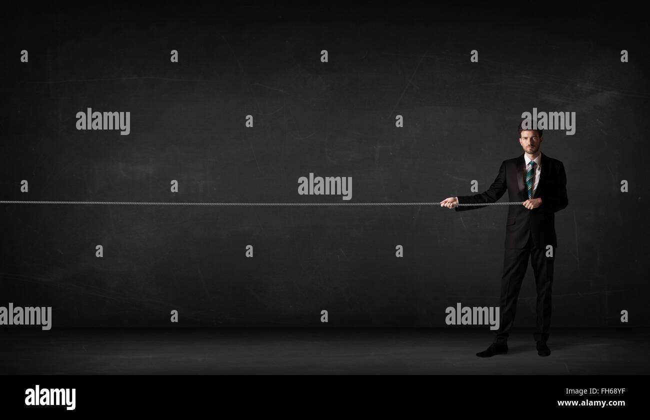 Businessman pulling rope on grey background Stock Photo - Alamy