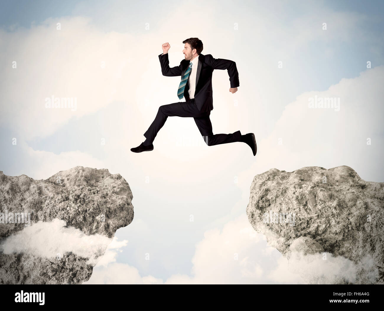 Happy business man jumping over a cliff Stock Photo - Alamy