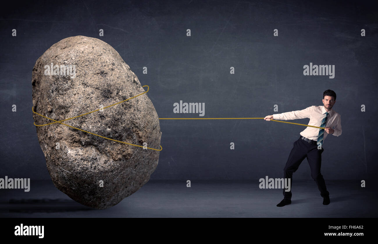Businessman pulling huge rock with a rope Stock Photo - Alamy