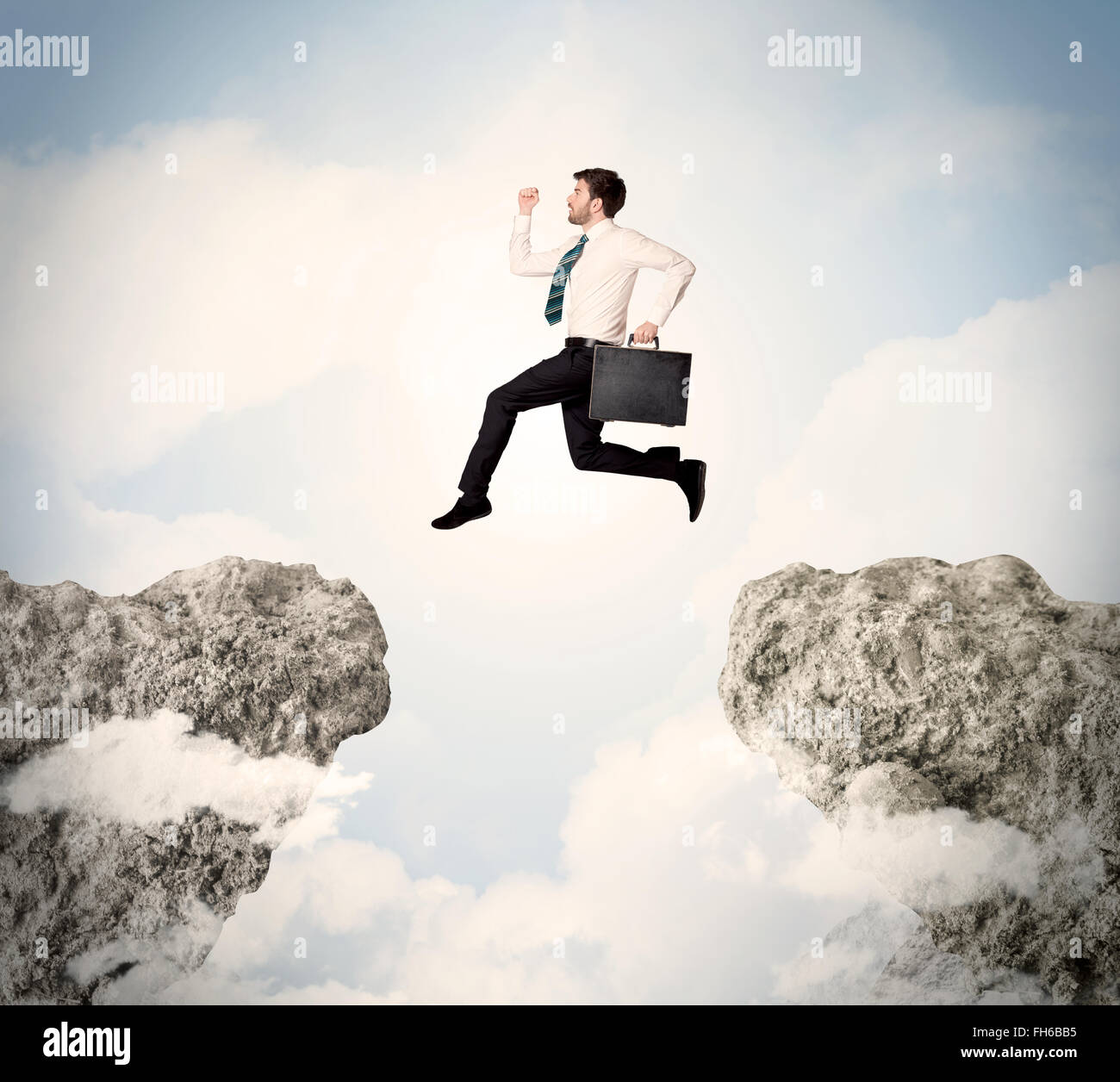 Happy business man jumping over a cliff Stock Photo - Alamy