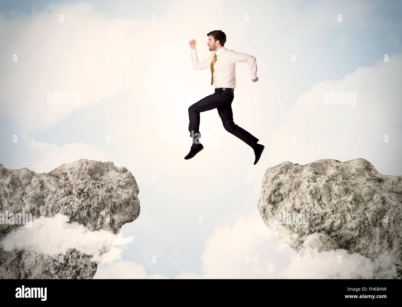 Happy business man jumping over a cliff Stock Photo - Alamy