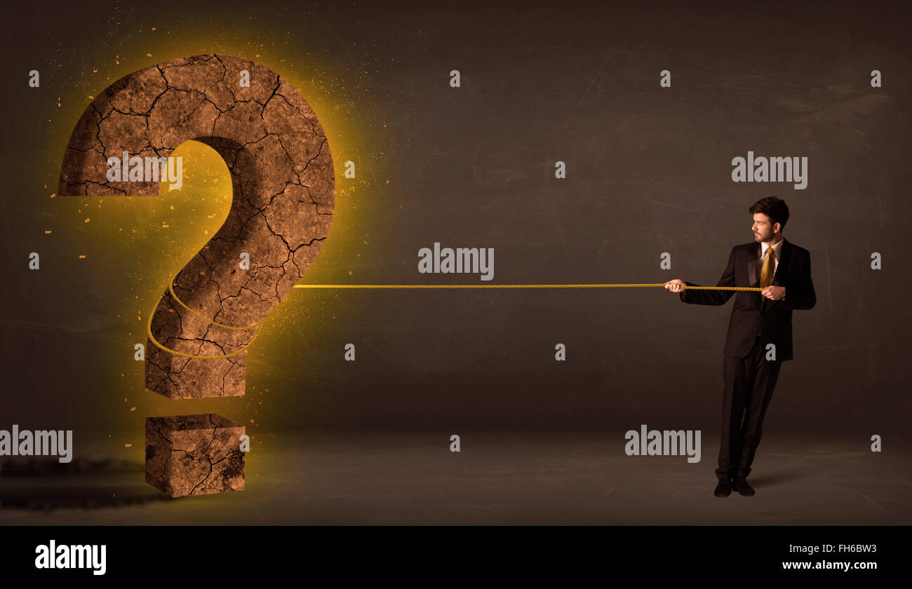 Business man pulling a big solid question mark stone Stock Photo - Alamy