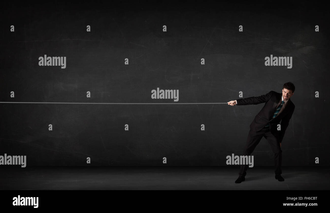 Businessman pulling rope on grey background Stock Photo - Alamy