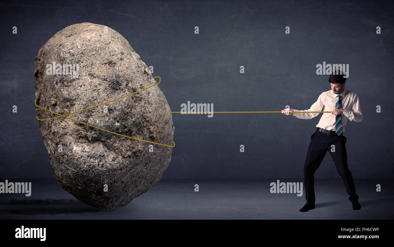 Businessman pulling huge rock with a rope Stock Photo - Alamy