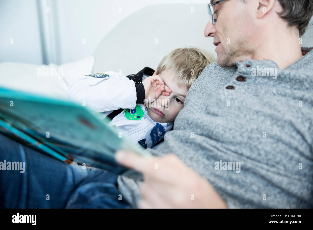 Father reading book to tired boy in spacesuit Stock Photo - Alamy