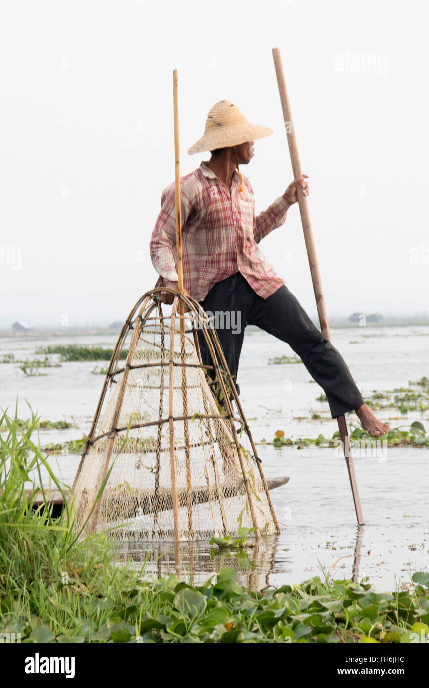 Fisherman uses one leg to row while fishing with a home made conical ...