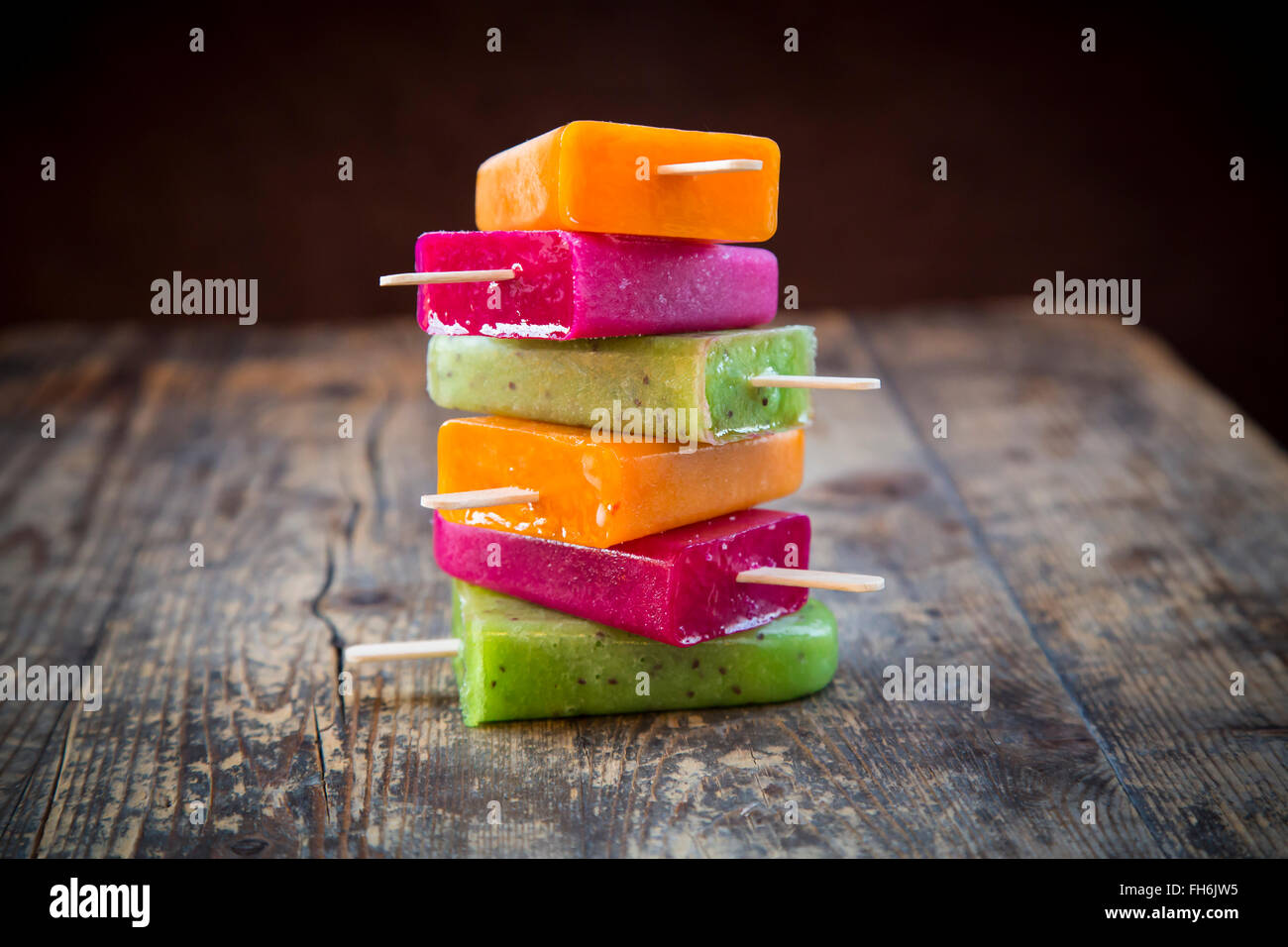 Stack of fruit smoothie ice lollies on dark wood Stock Photo - Alamy
