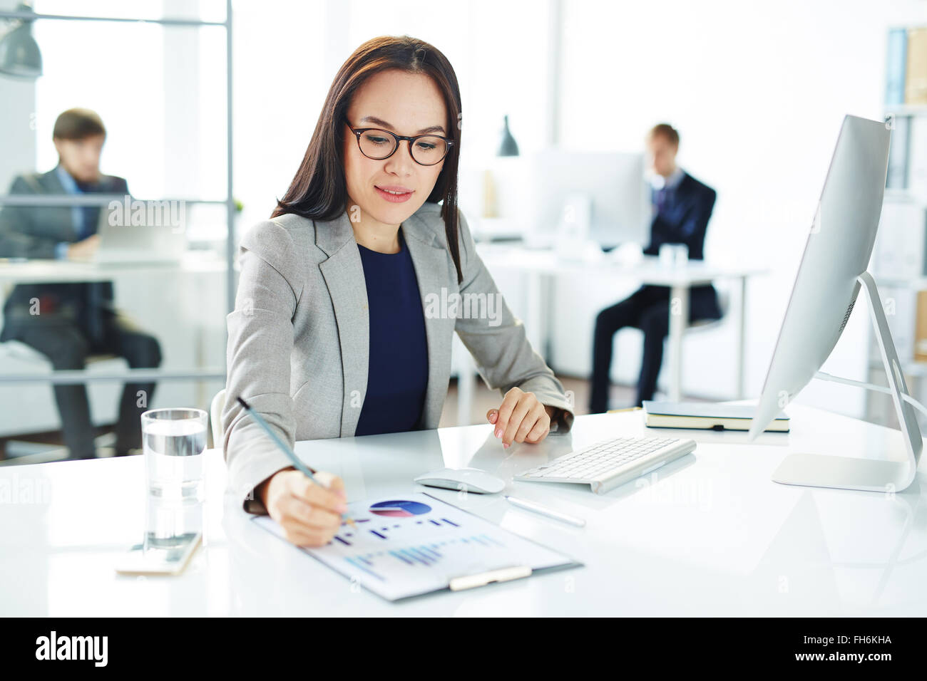 Pretty secretary analyzing data at workplace in front of computer Stock ...
