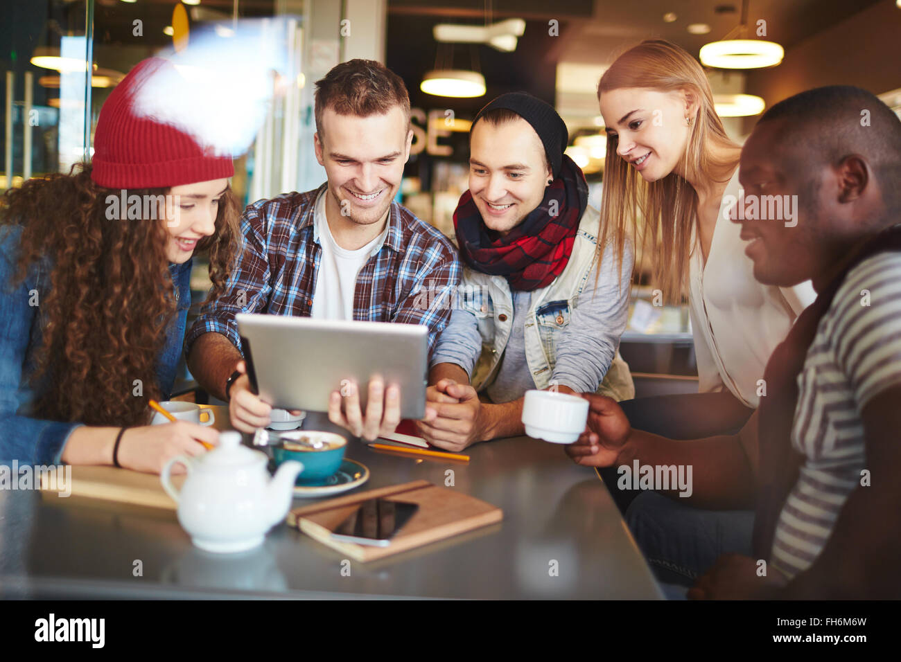 Friendly teenagers in casual-wear having tea break in cafe Stock Photo ...
