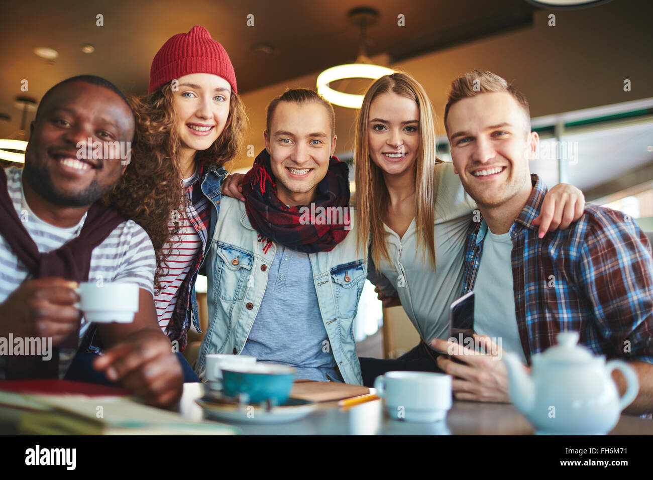 Modern teenagers looking at camera with smiles in cafe Stock Photo - Alamy