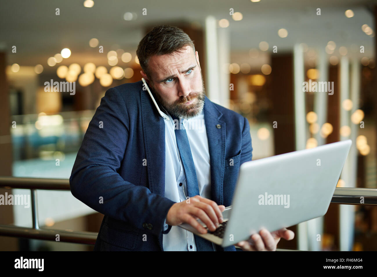 Contemporary business agent typing and speaking on the phone Stock ...