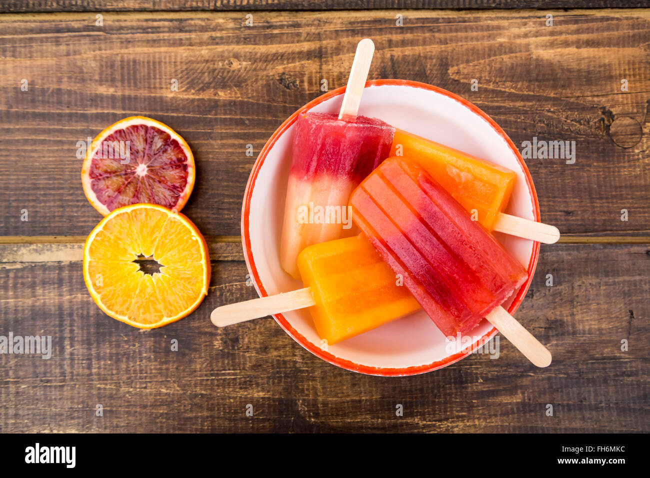 Bowl of different homemade orange ice lollies Stock Photo - Alamy