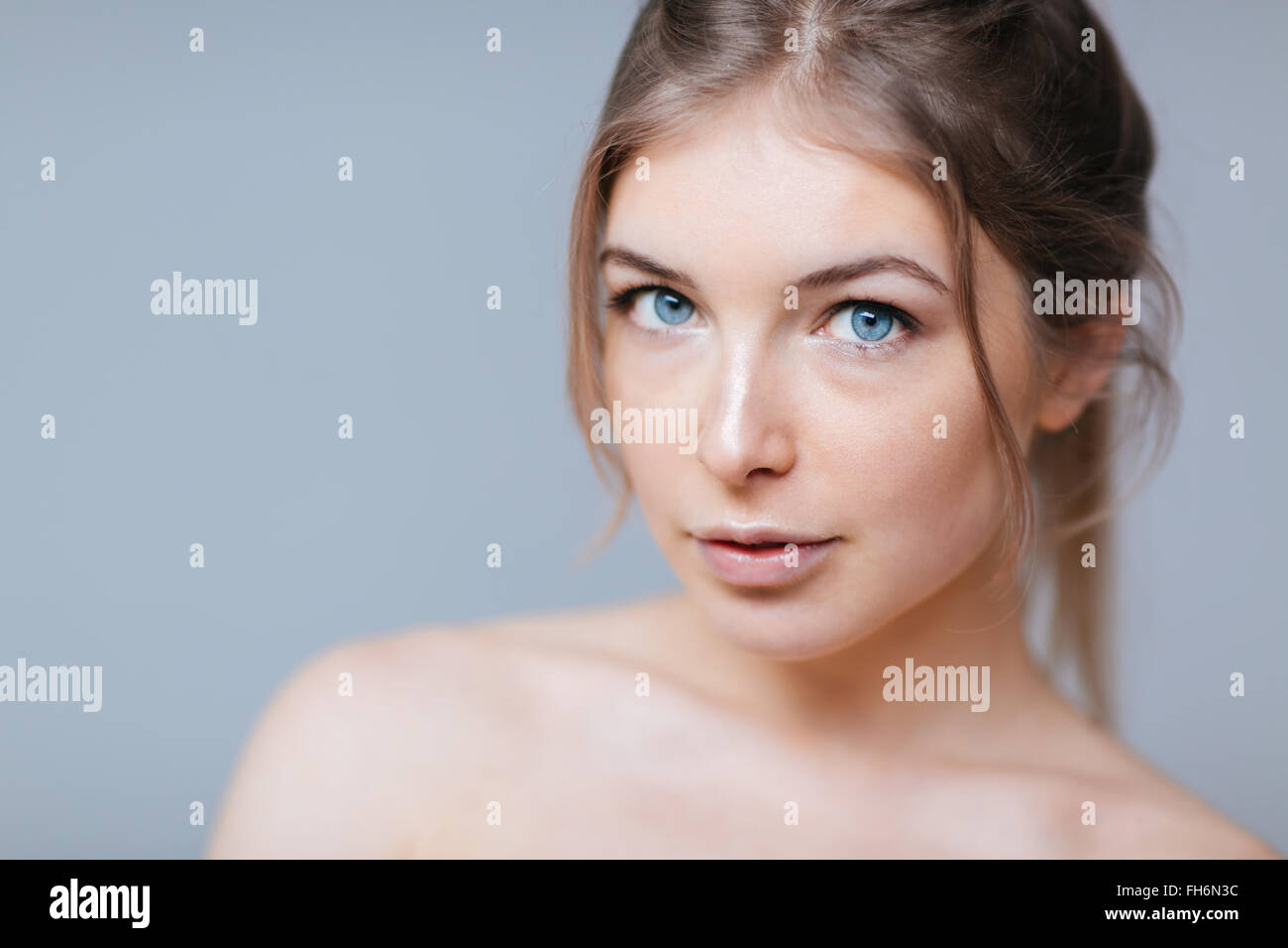 Beauty portrait of a lovely woman with fresh skin standing over gray ...