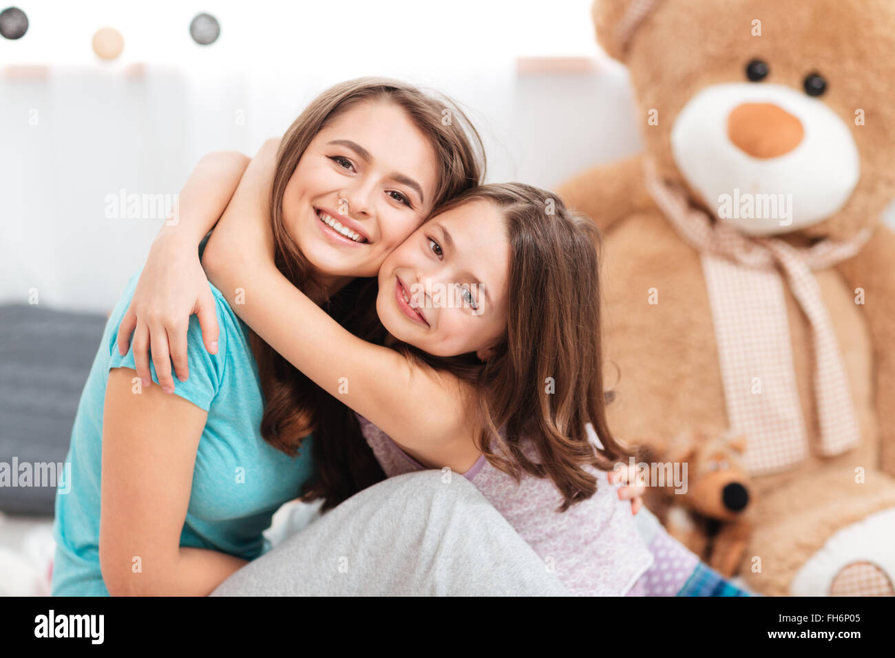 Two cheerful charming sisters smiling and embracing at home Stock Photo ...