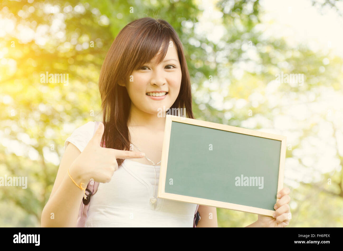 Young Asian college girl student standing on campus lawn, hand pointing ...