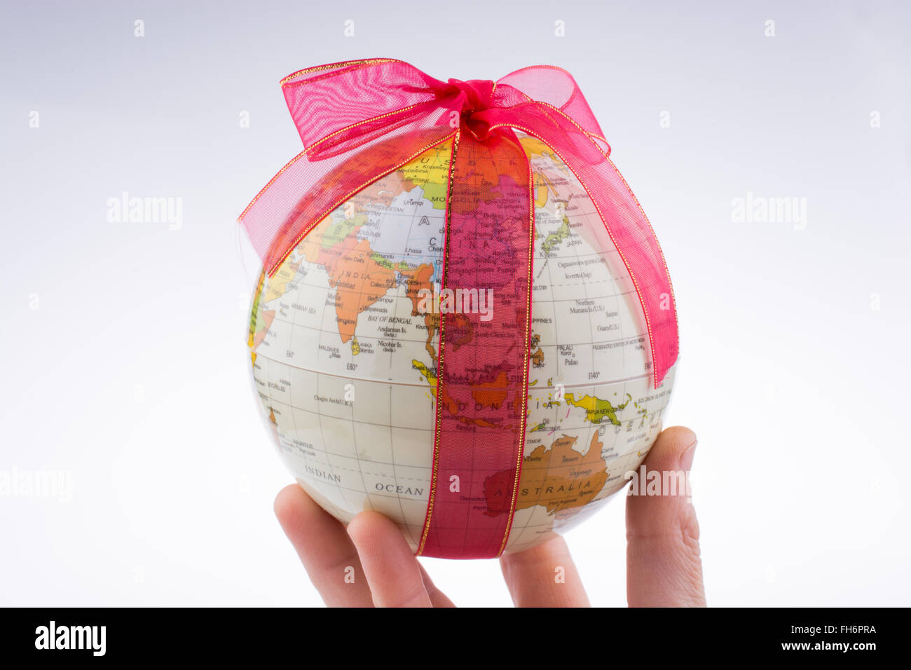 Globe tied with red ribbon on a white background Stock Photo - Alamy