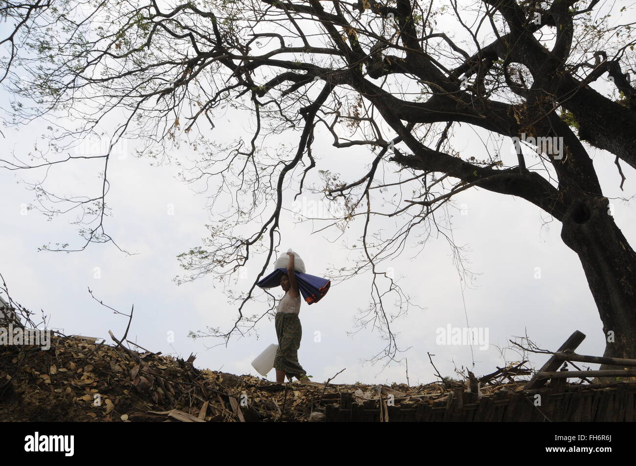 A Cyclone Nargis survivor carries food and water container donated by ...