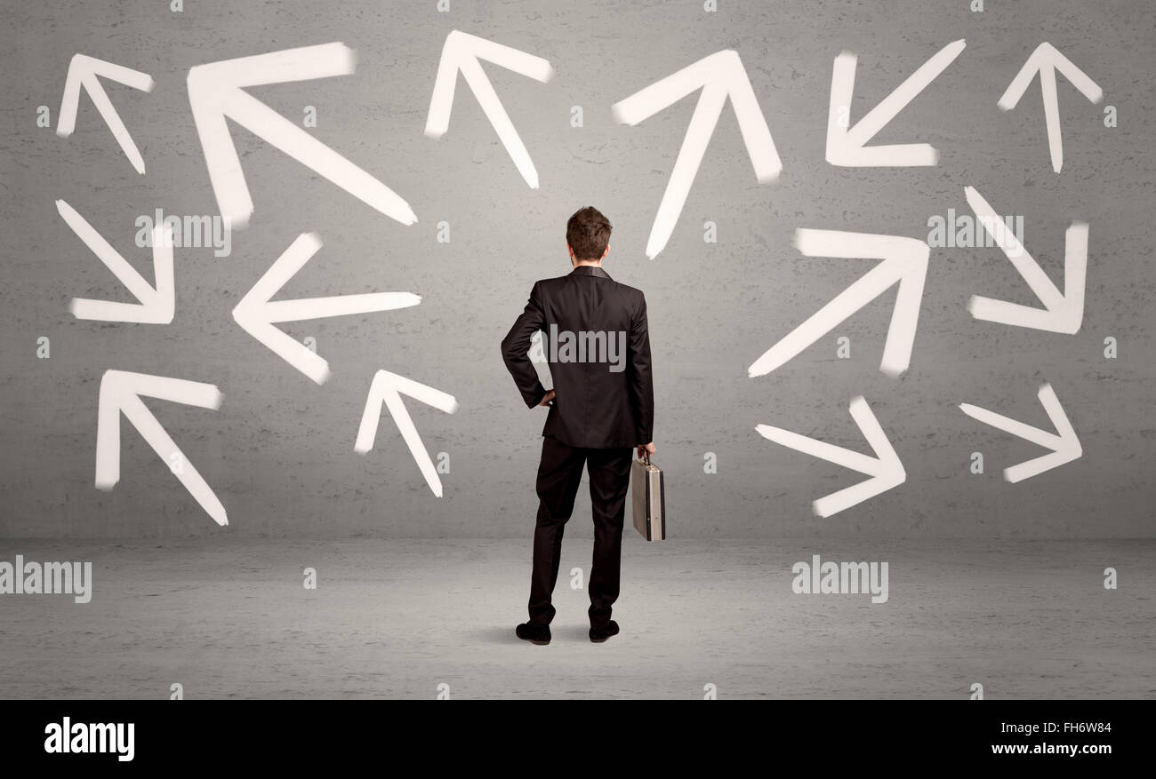 Confused salesman with arrows on wall Stock Photo - Alamy