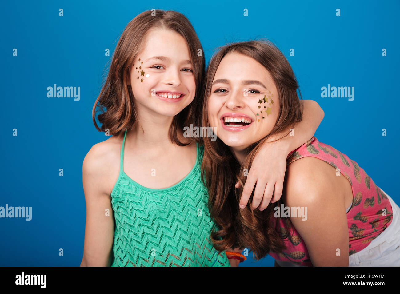 Portrait of two happy lovely sisters with decorations on cheeks ...