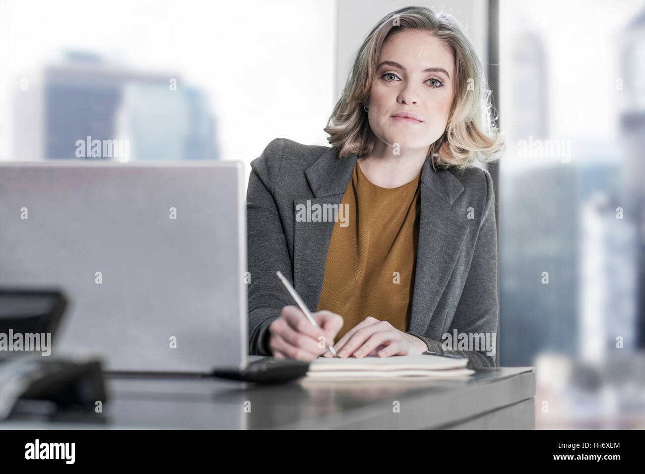 Portrait of woman at office desk writing Stock Photo - Alamy