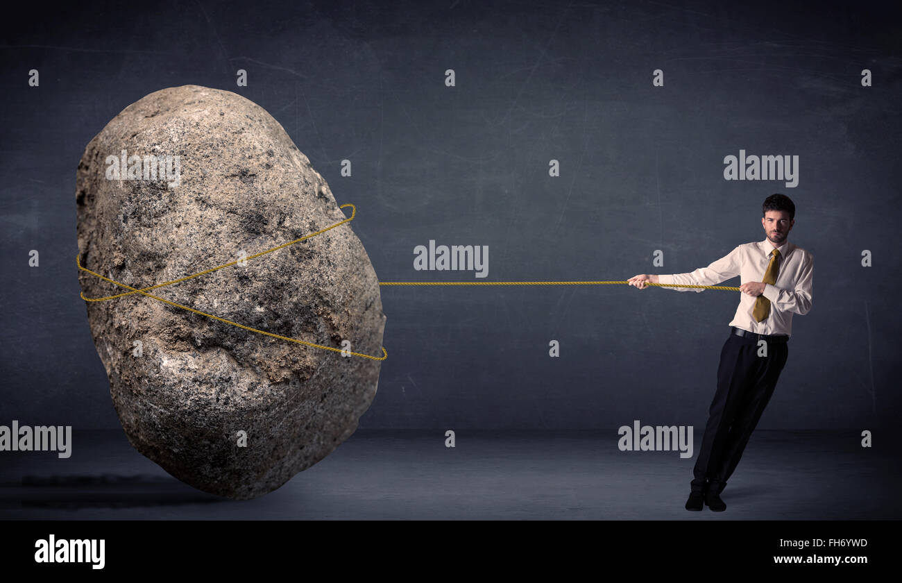 Businessman pulling huge rock with a rope Stock Photo - Alamy