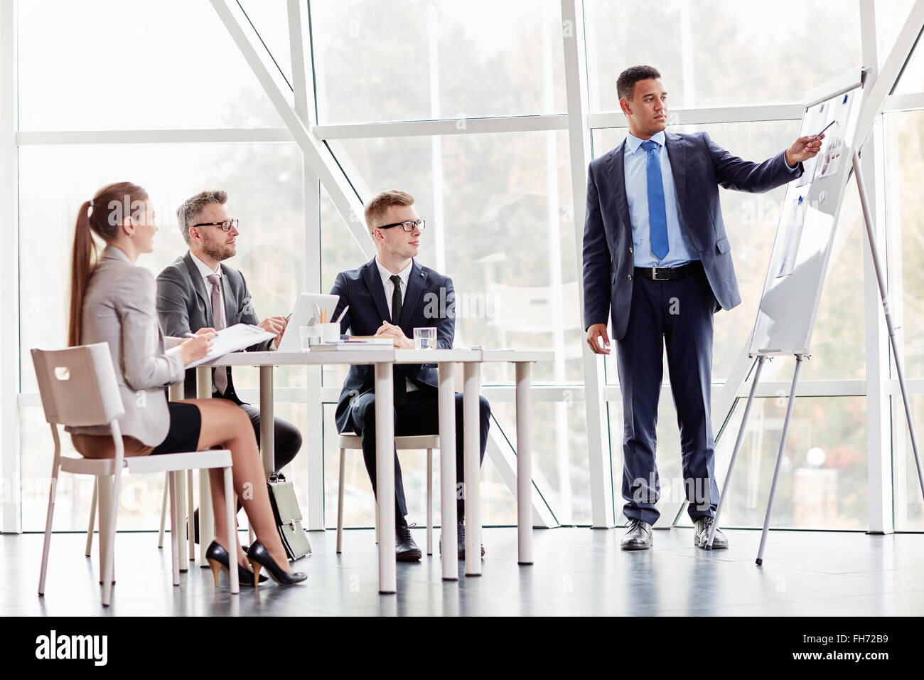Successful businessman pointing at paper with data on whiteboard during ...