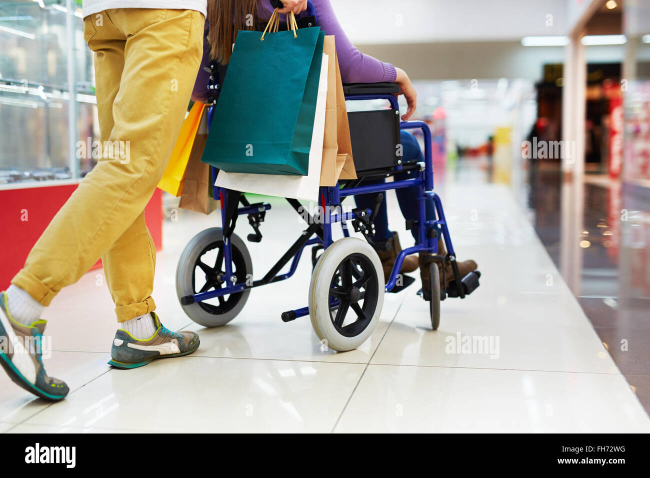 Caring guy helping his girlfriend on wheelchair with shopping Stock ...