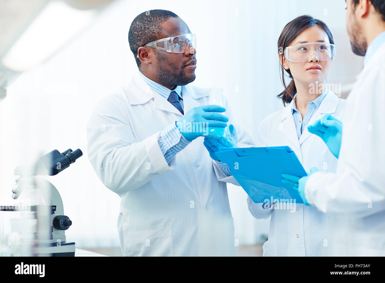 Group of modern chemists discussing new substance in lab Stock Photo ...