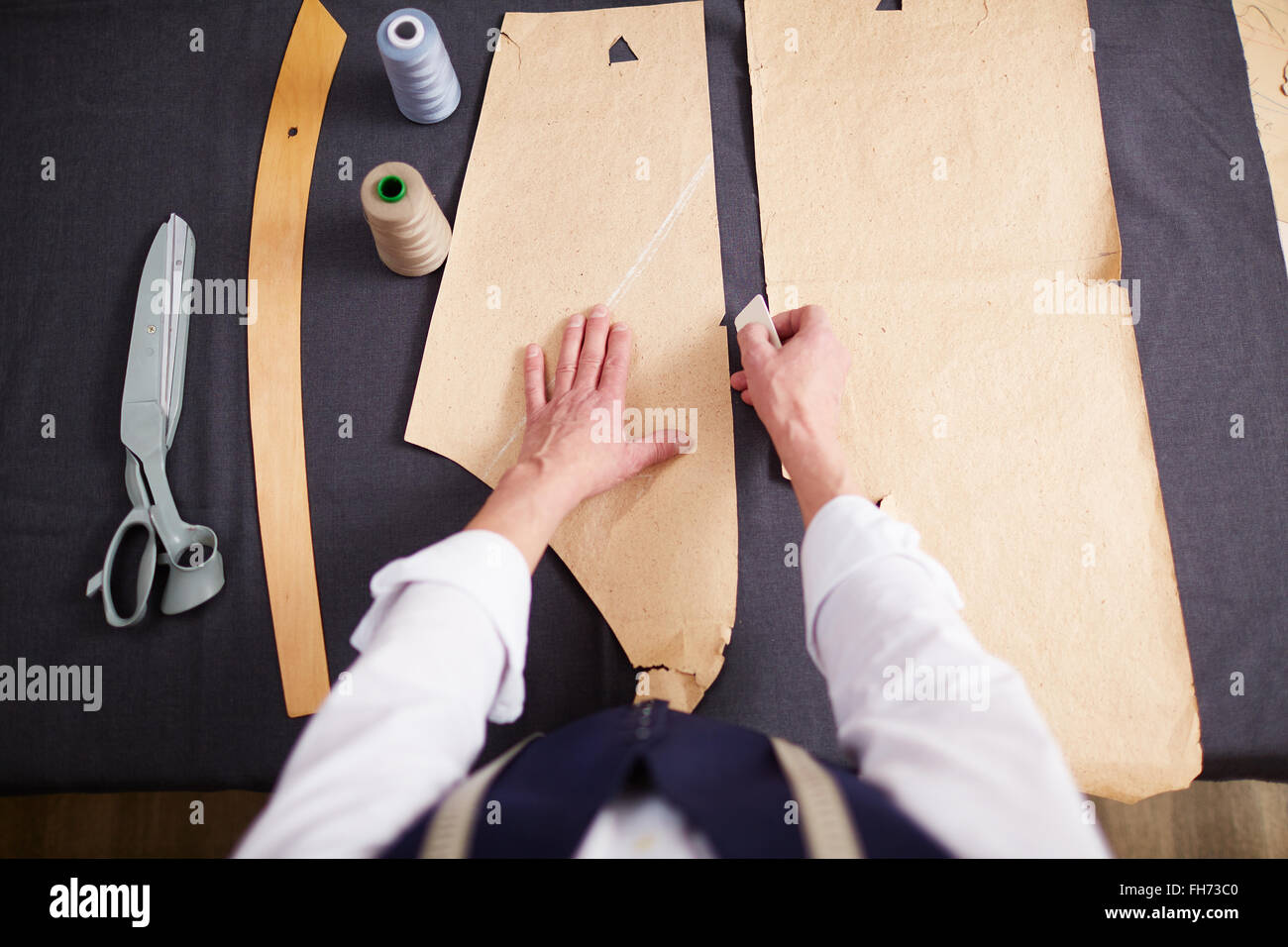 Modern tailor drawing contours of paper patterns with chalk Stock Photo ...