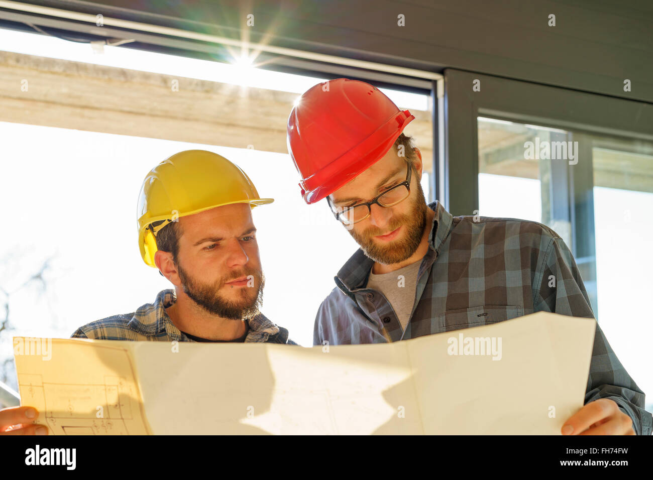 Two craftsmen looking at building plan in construction site Stock Photo ...