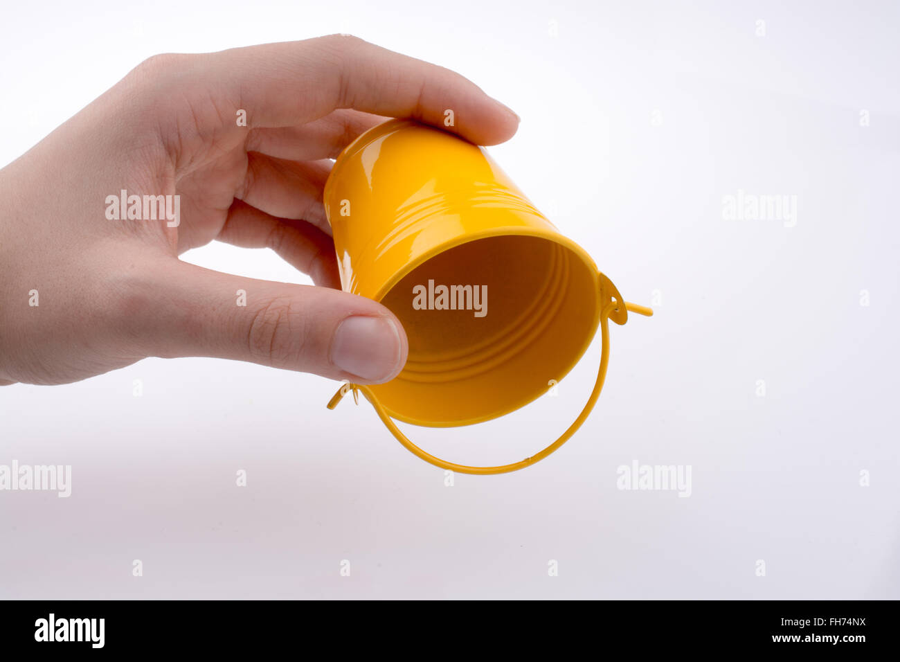 Hand holding a yellow bucket on a white background Stock Photo - Alamy