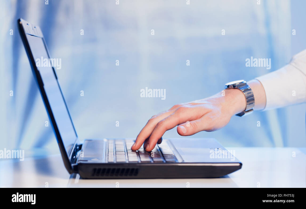 Businessman pressing modern laptop computer on colorful background ...