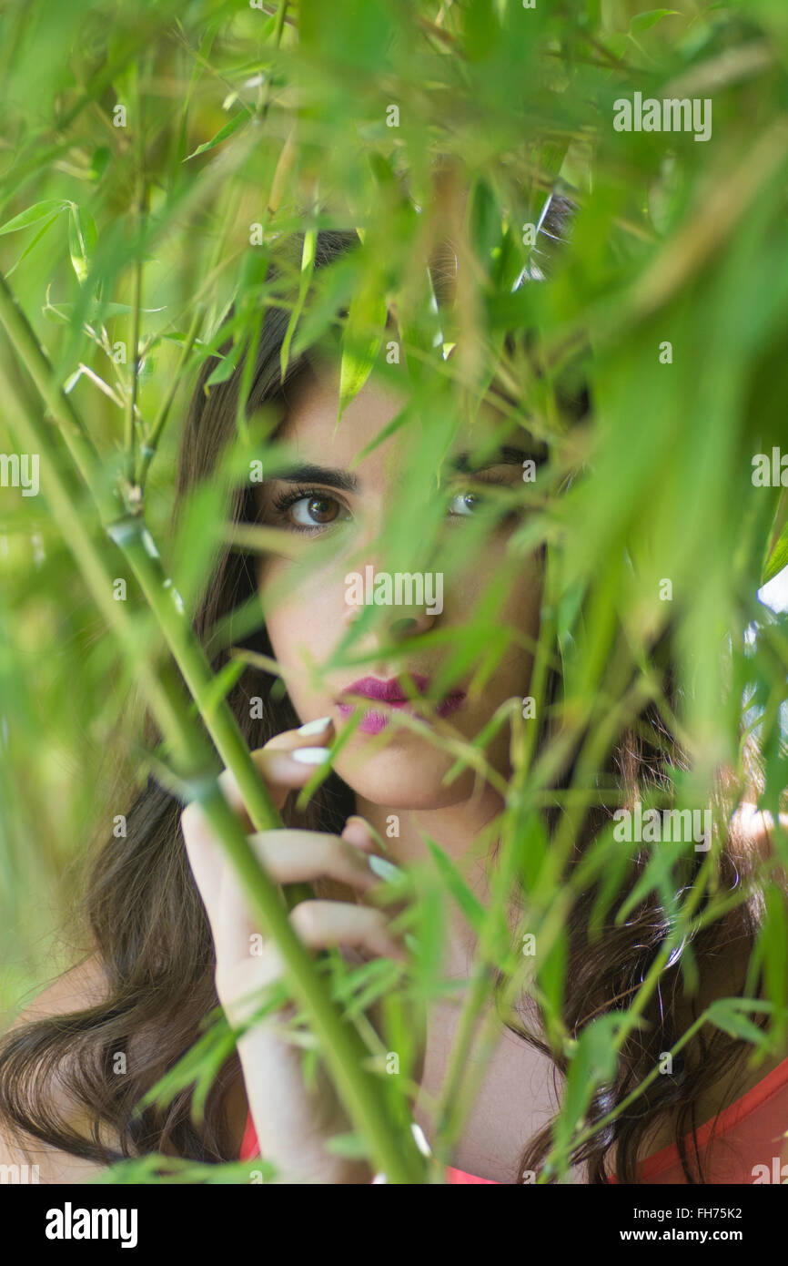 Scared young woman hiding behind trees Stock Photo - Alamy