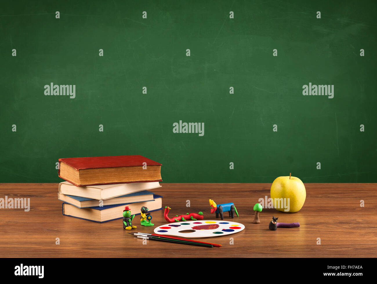 School items on desk with empty chalkboard Stock Photo - Alamy