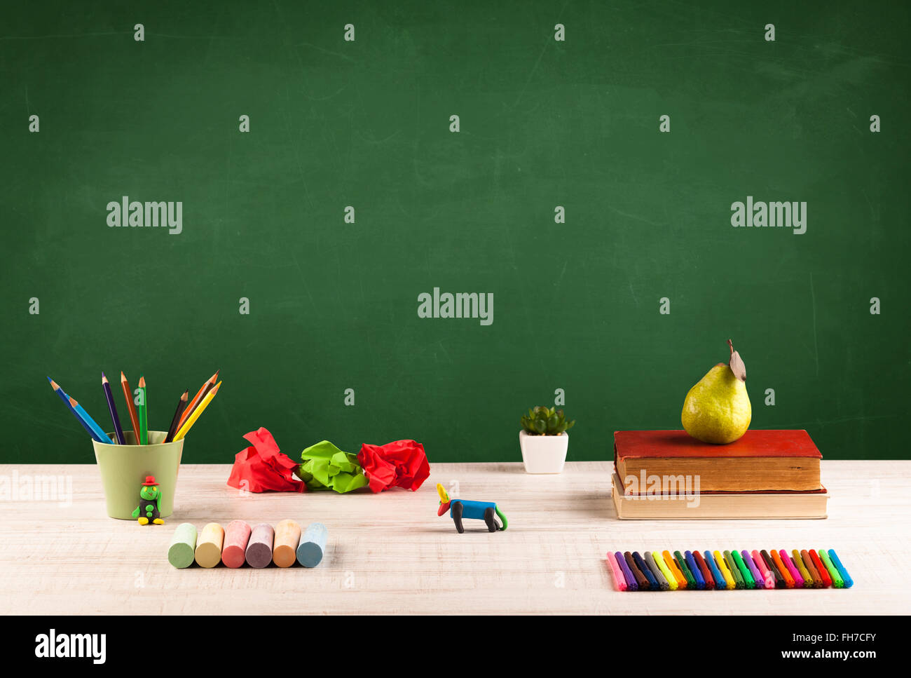 School items on desk with empty chalkboard Stock Photo - Alamy
