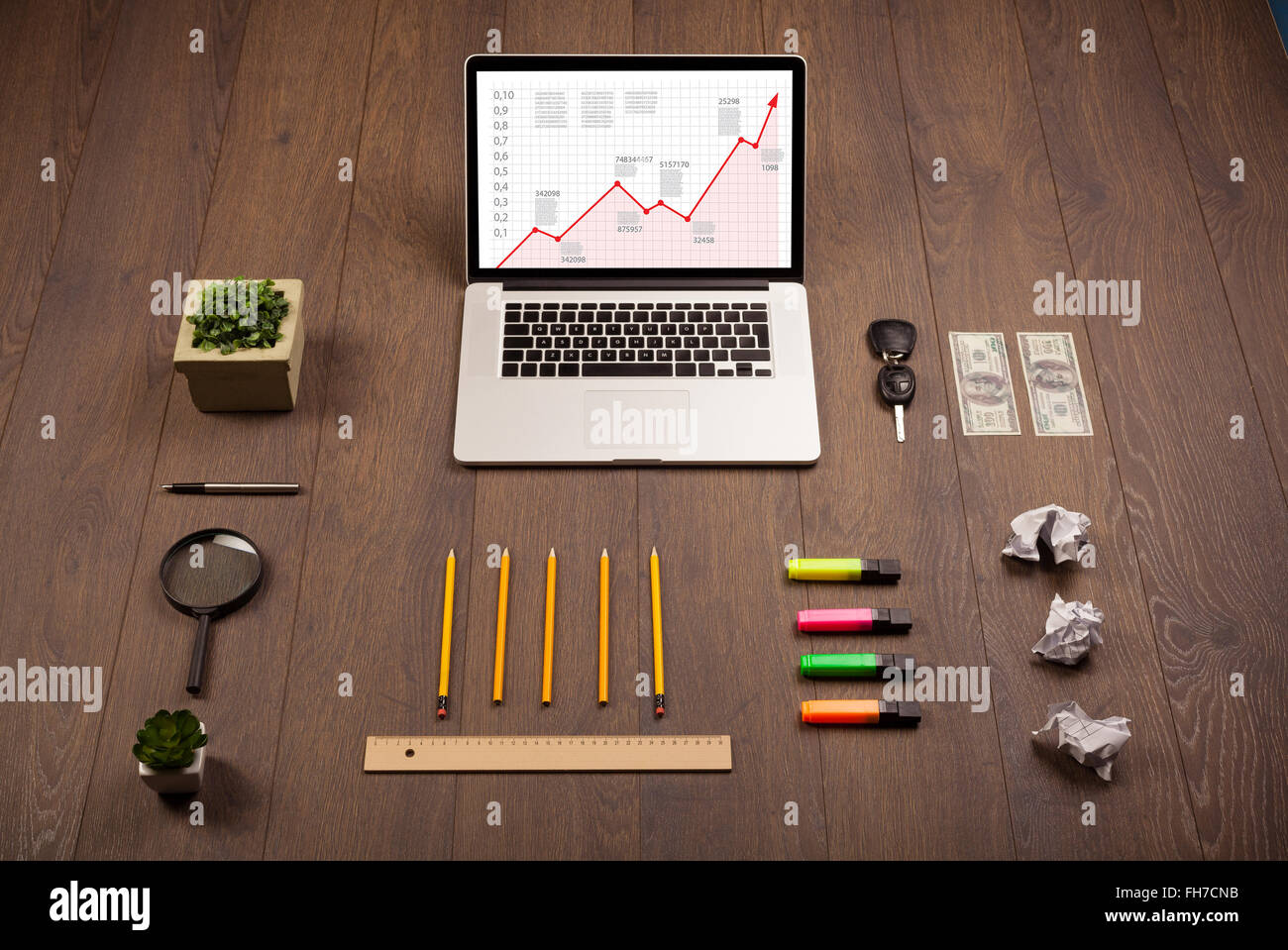 Computer desk with laptop and red arrow chart in screen Stock Photo - Alamy