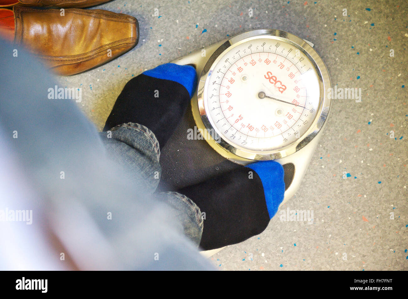 Patient standing on scales during a medical checkup at the local NHS ...