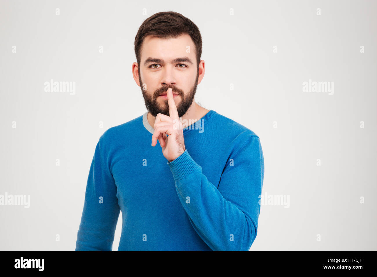 Casual man showing finger over lips isolated on a white background ...